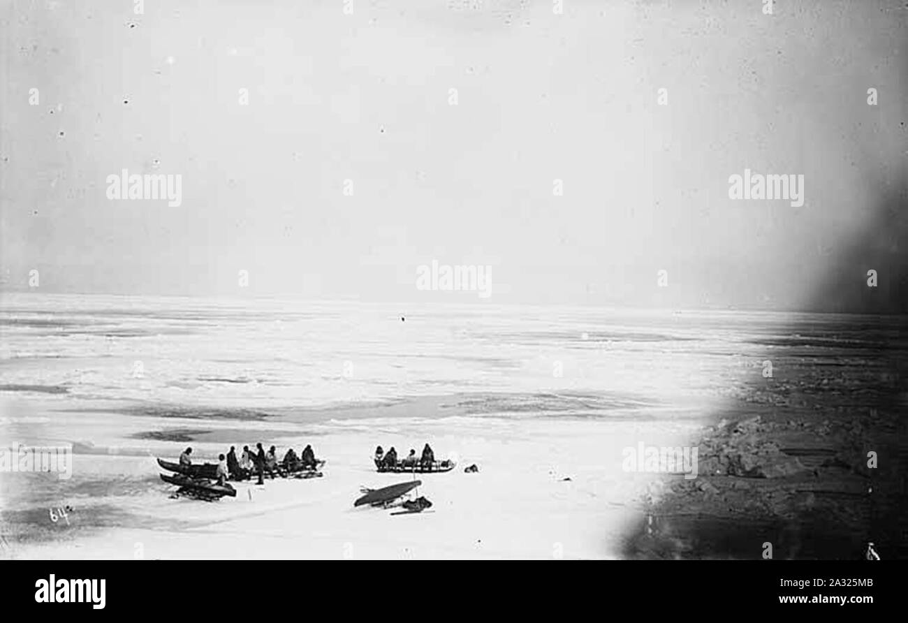 Eskimos with sleds and kayaks on an ice flow two miles offshore from ...