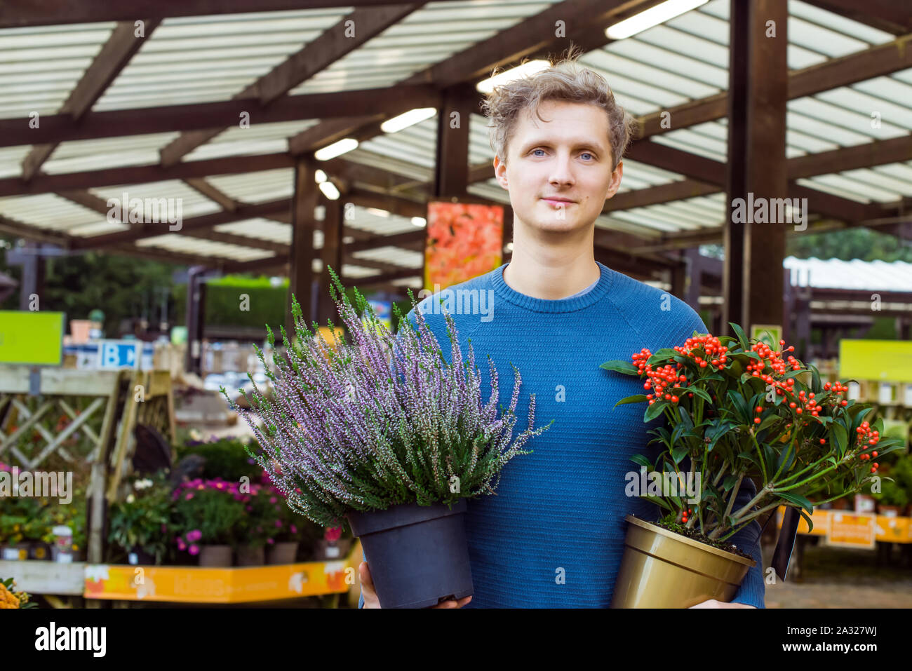 Young caucasian man selecting potted plants at a garden centre. Autumn ...