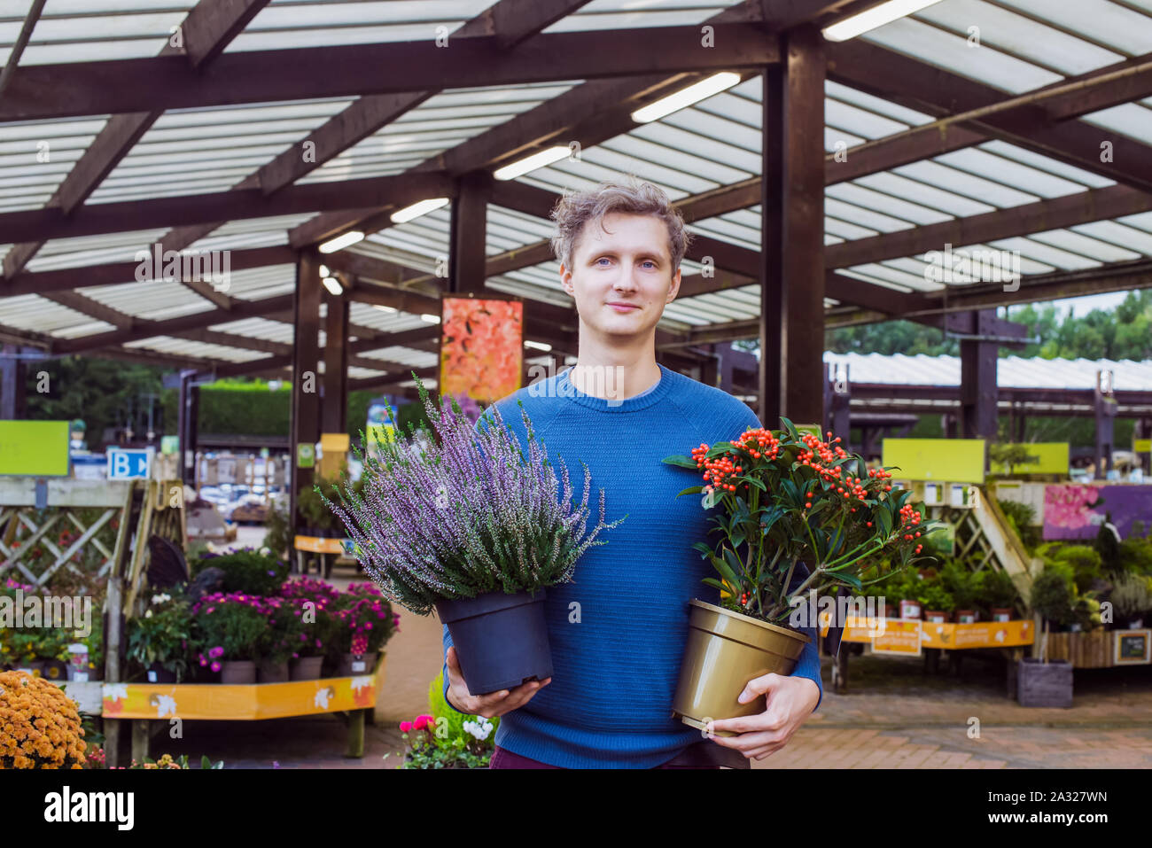 Young caucasian man selecting potted plants at a garden centre. Autumn ...