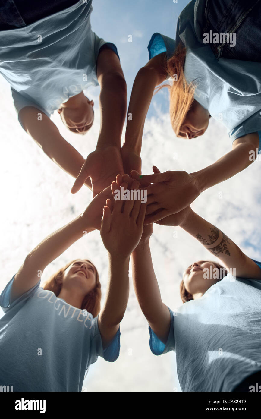Volunteering. Young people volunteers outdoors standing hands together ...