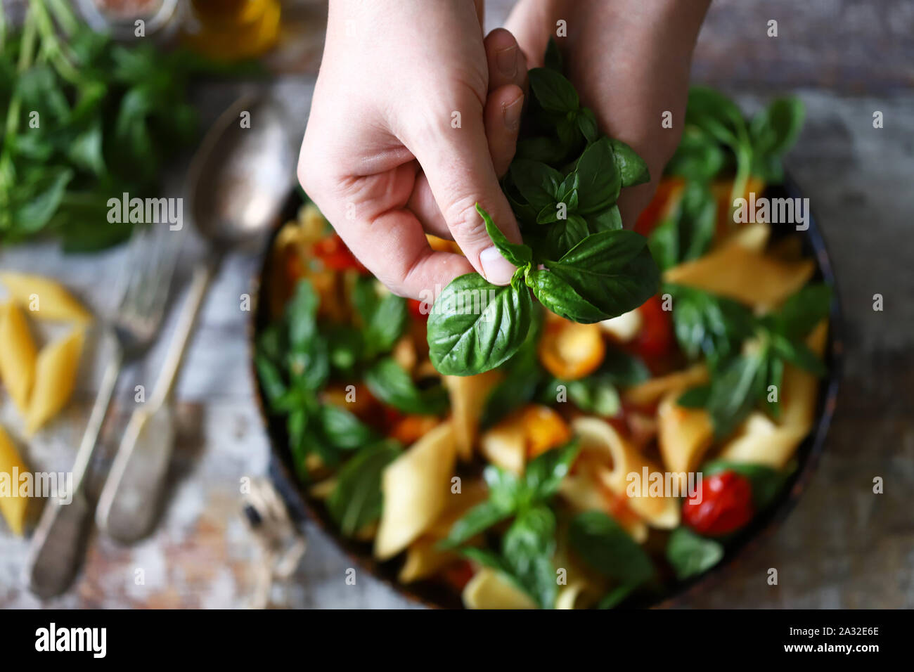 Hands of a chef with basil for cooking Italian pasta. Cooking one pan ...