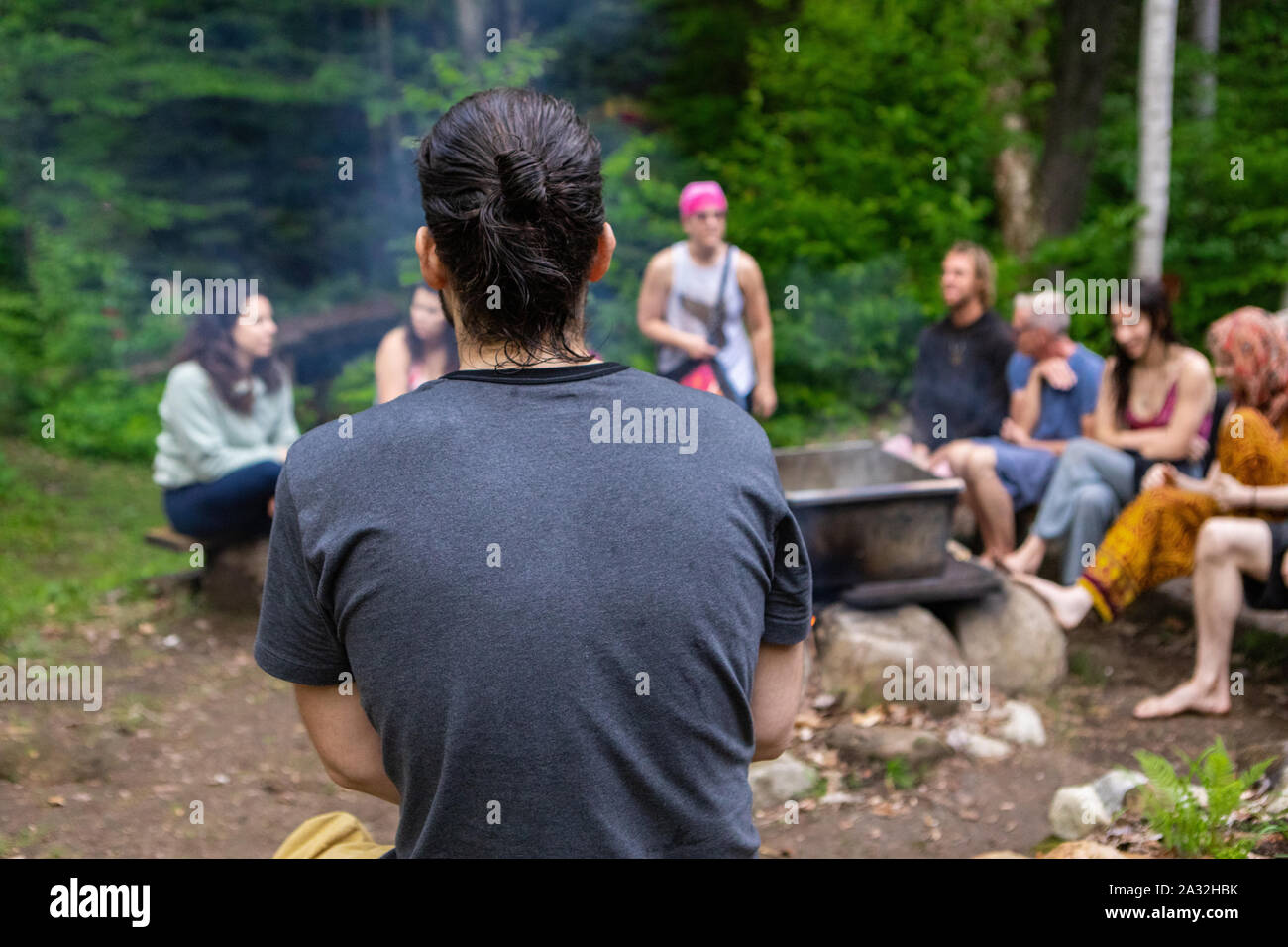 A closeup and back view of a caucasian guy with a hair bun and grey t ...