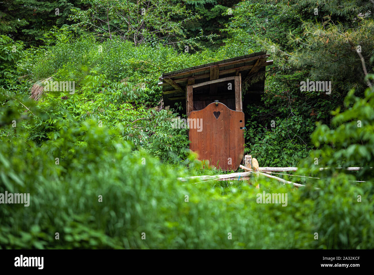 A quaint wooden restroom shack with wooden door and heart shape hole is ...