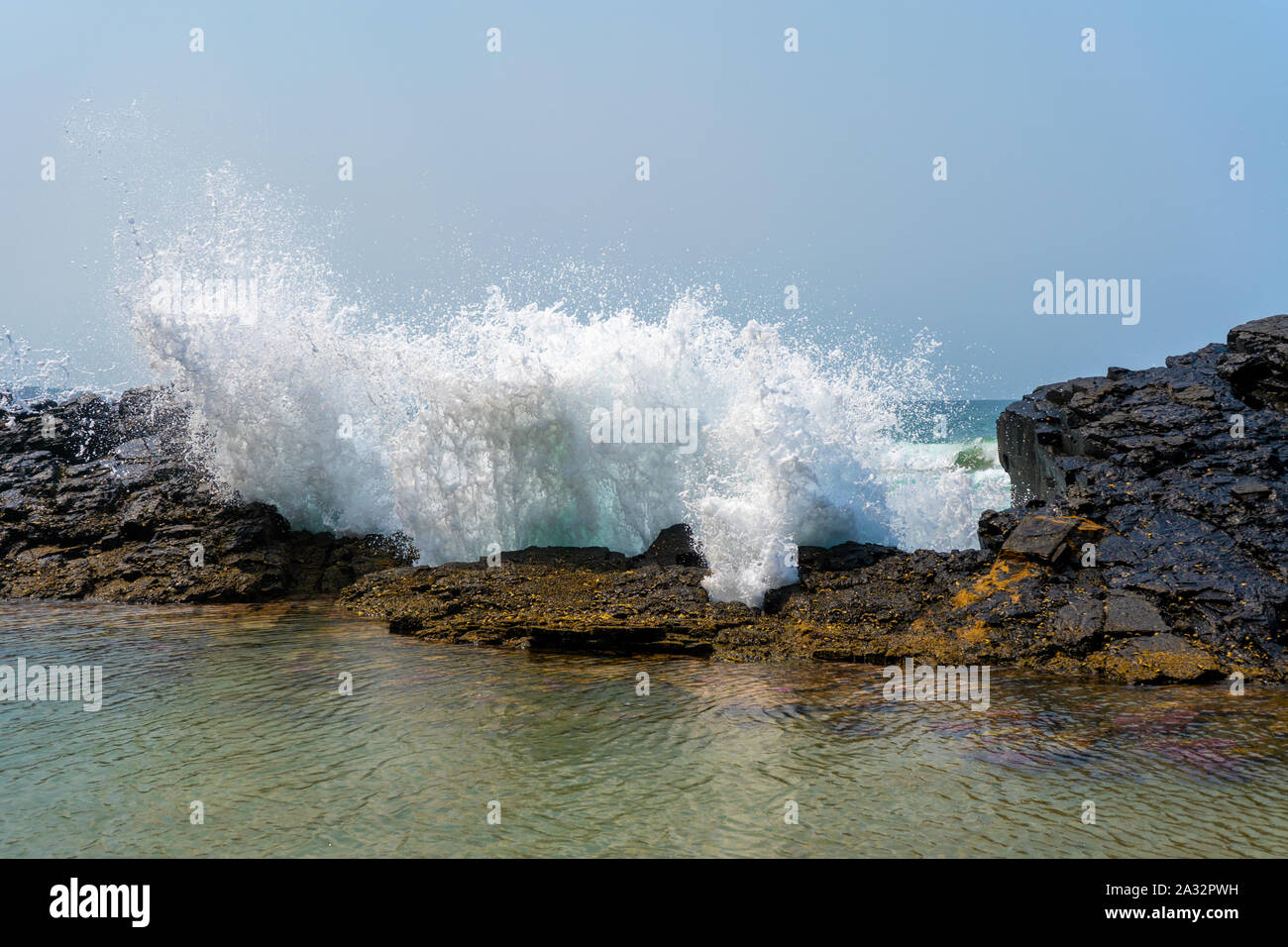 Wave splashing over the rocks rocks at the beach on the Dolphin Coast ...