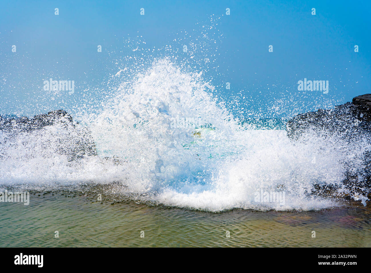 Wave splashing over the rocks rocks at the beach on the Dolphin Coast ...