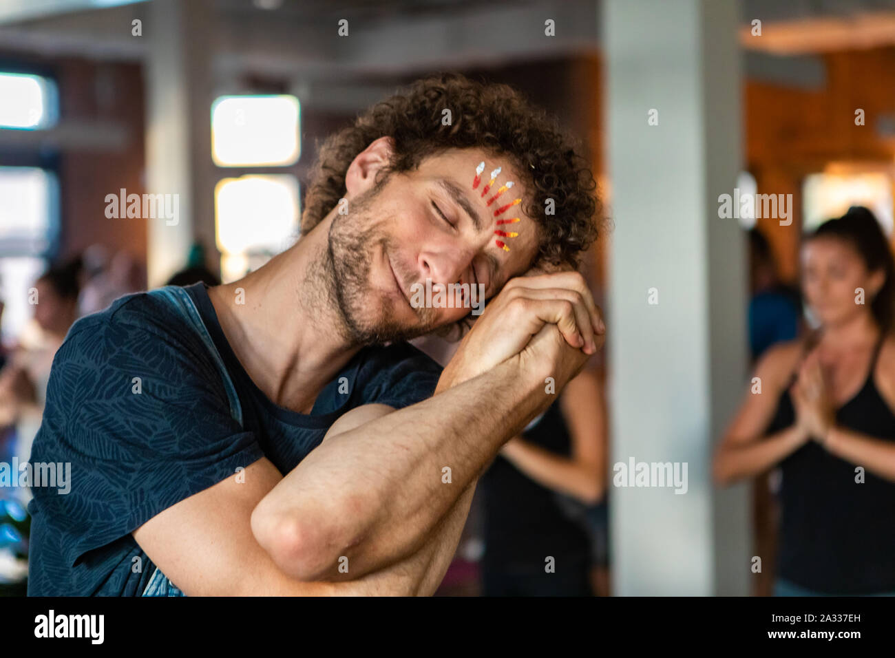 A young and spiritual Caucasian guy is seen up close, resting head on ...