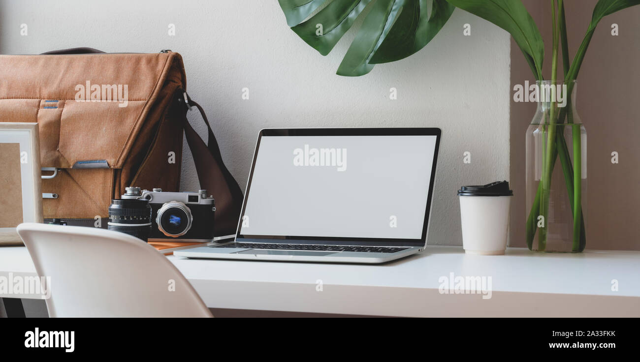Comfortable workspace with blank screen laptop computer with mailbag ...