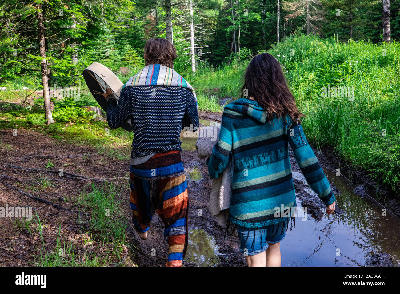 A young mystical couple are seen walking by a rural brook in dense ...