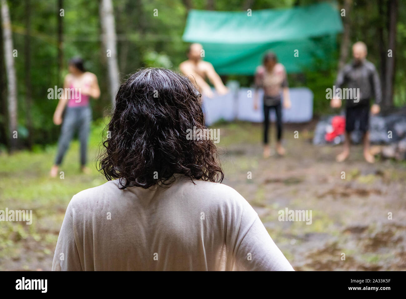 A woman with shoulder length black curly hair is viewed from behind as ...