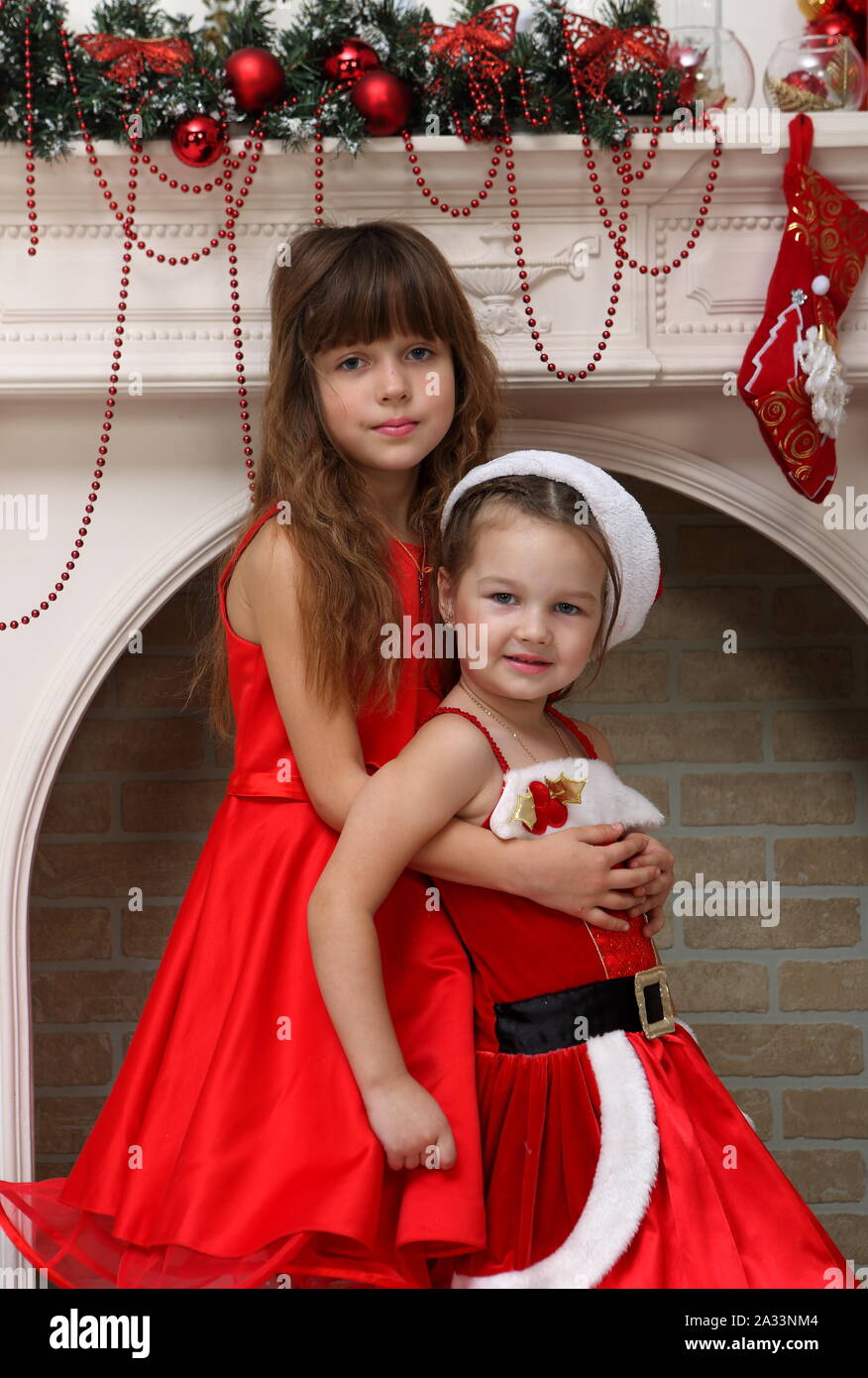 Two girls in red dresses near the fireplace Stock Photo - Alamy