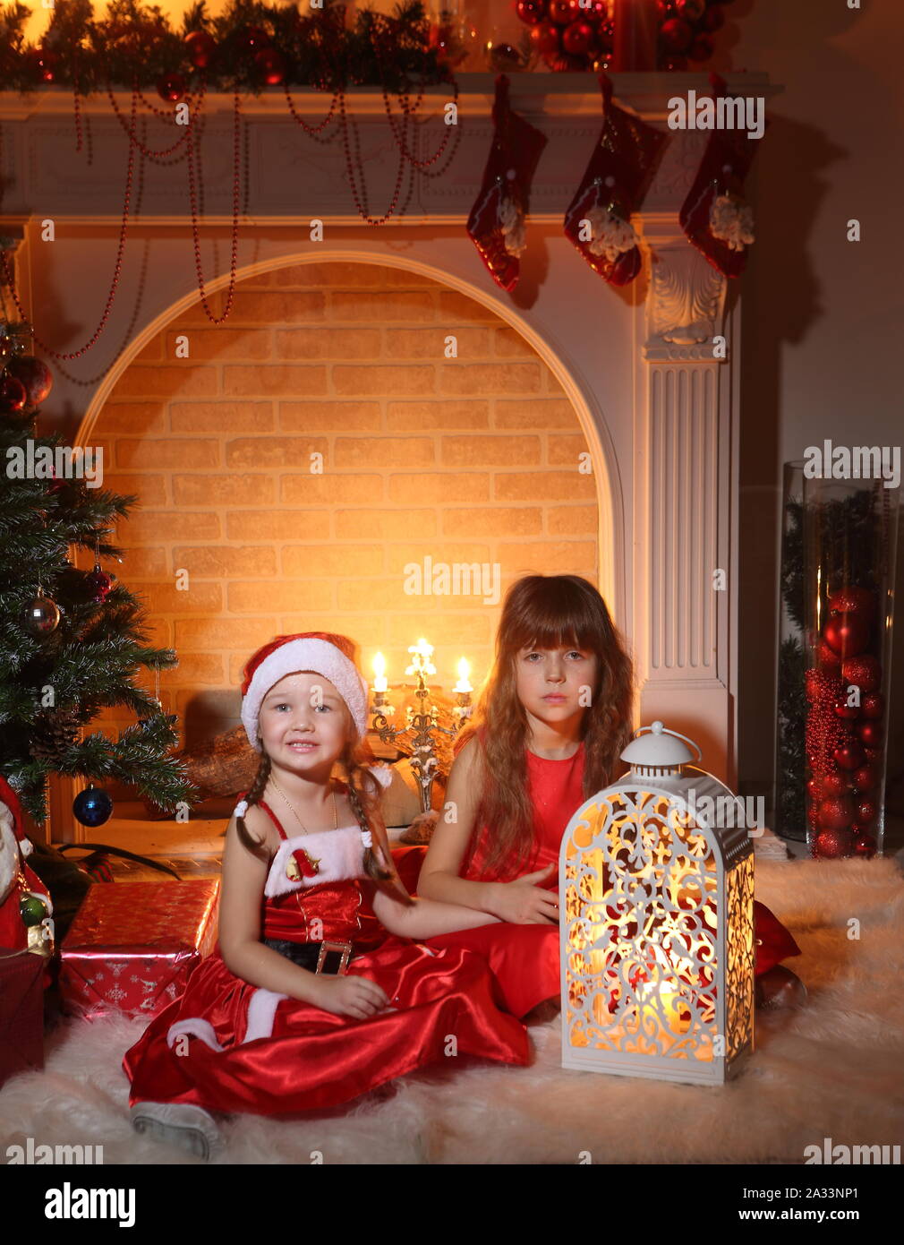 Two girls in red dresses near the fireplace Stock Photo - Alamy