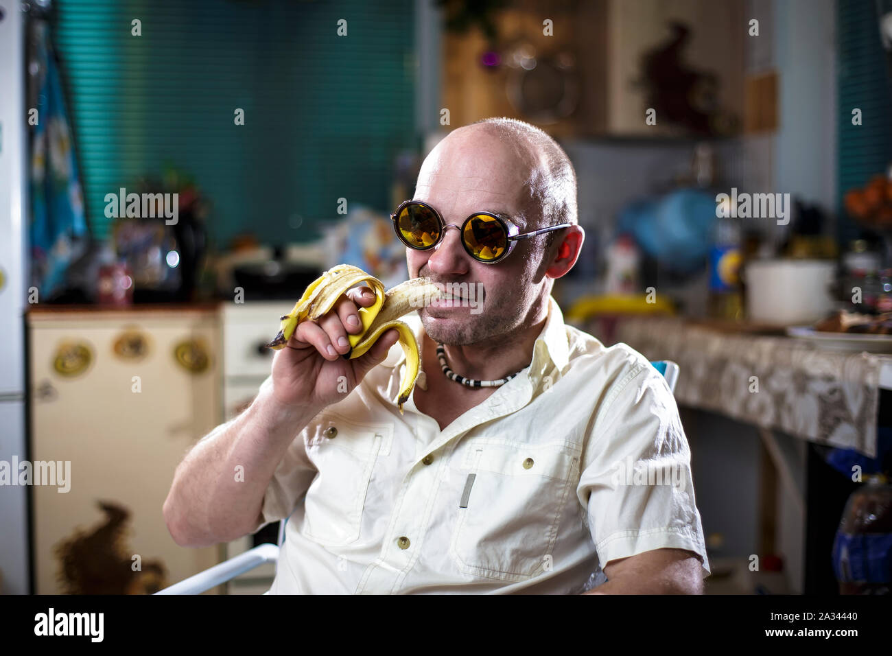 Man in stylish yellow sunglasses sitting relaxed in a chair and eating ...