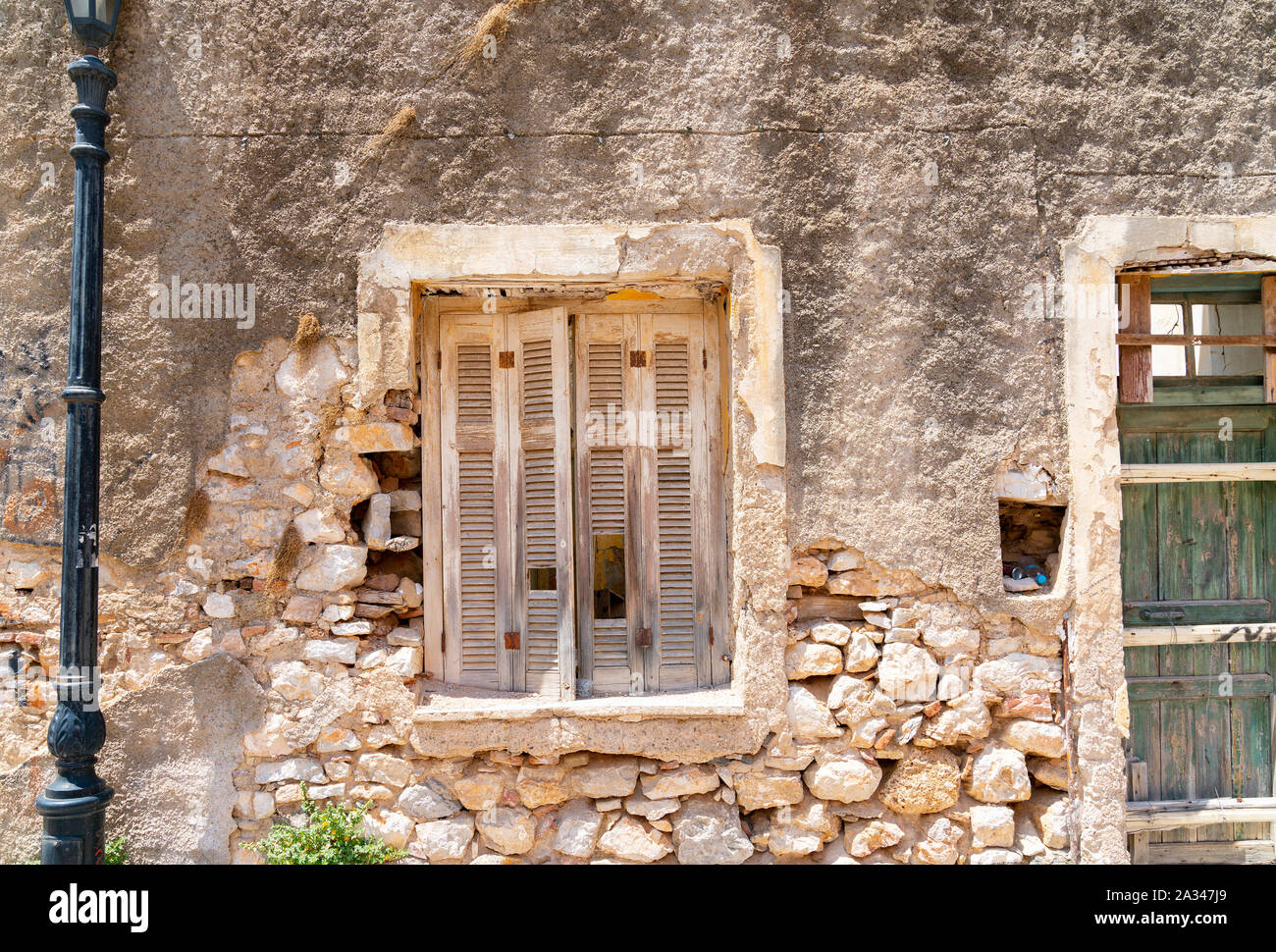 Old deteriorating stone wall with closed wooden shutters in rustic and ...