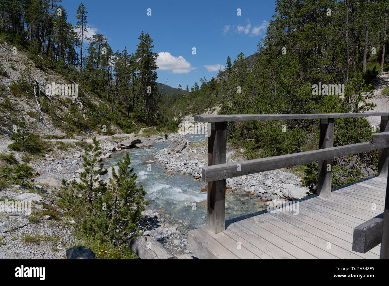 Wooden bridge over a ice cold mountain brook in a wild romantic natural ...