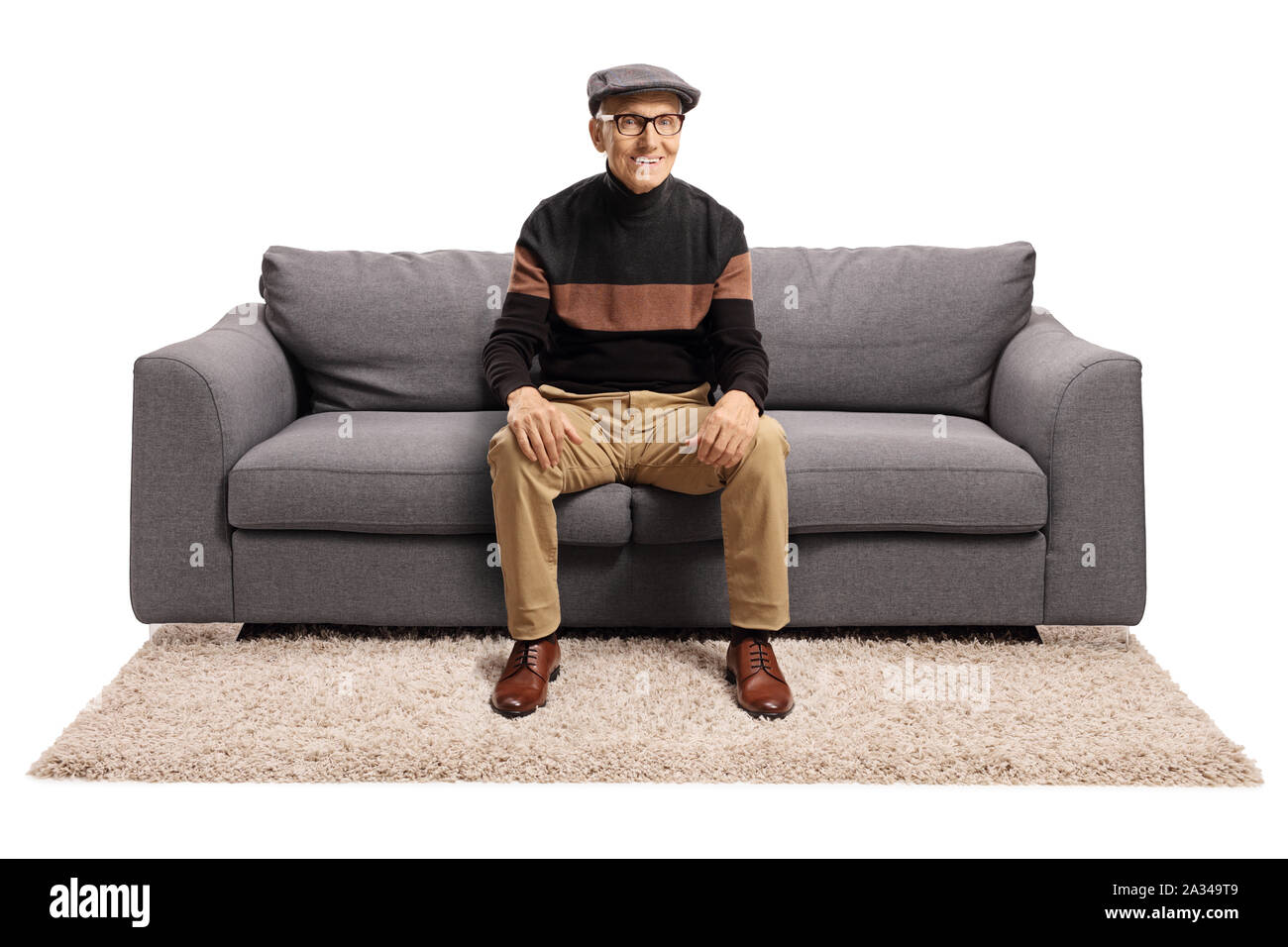 Elderly man sitting on a sofa and smiling isolated on white background ...