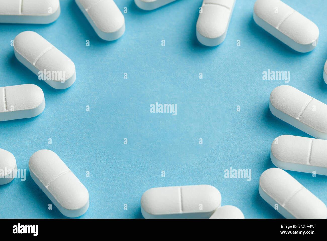 White pills on blue background. One tablet is broken in half, reducing ...