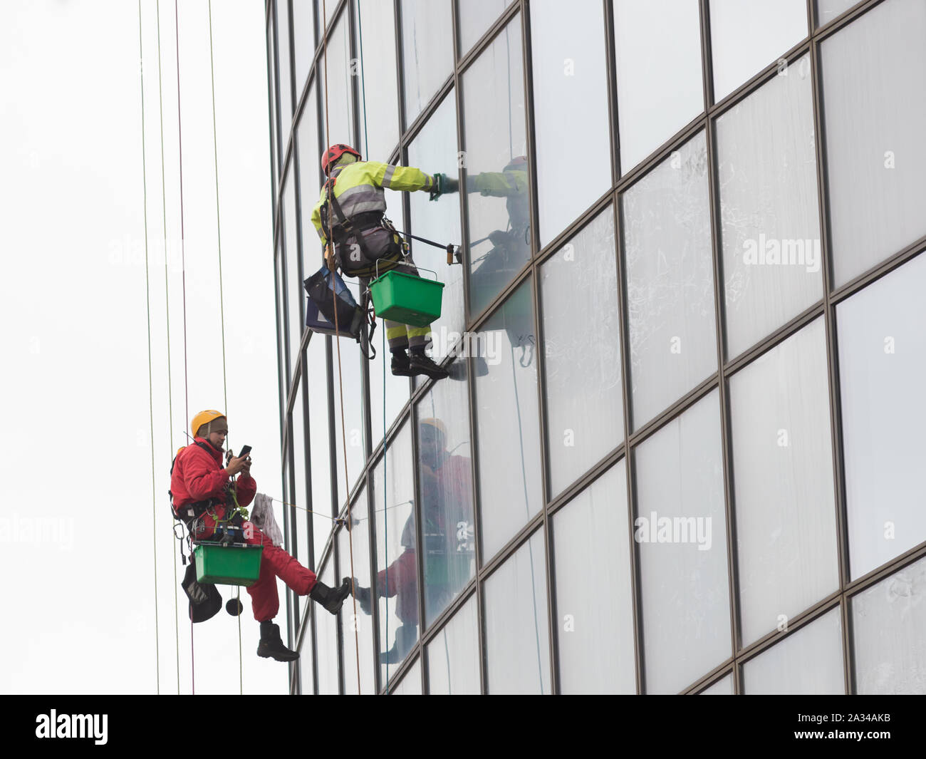 Two men workers hanging on ropes by the exterior windows of a ...
