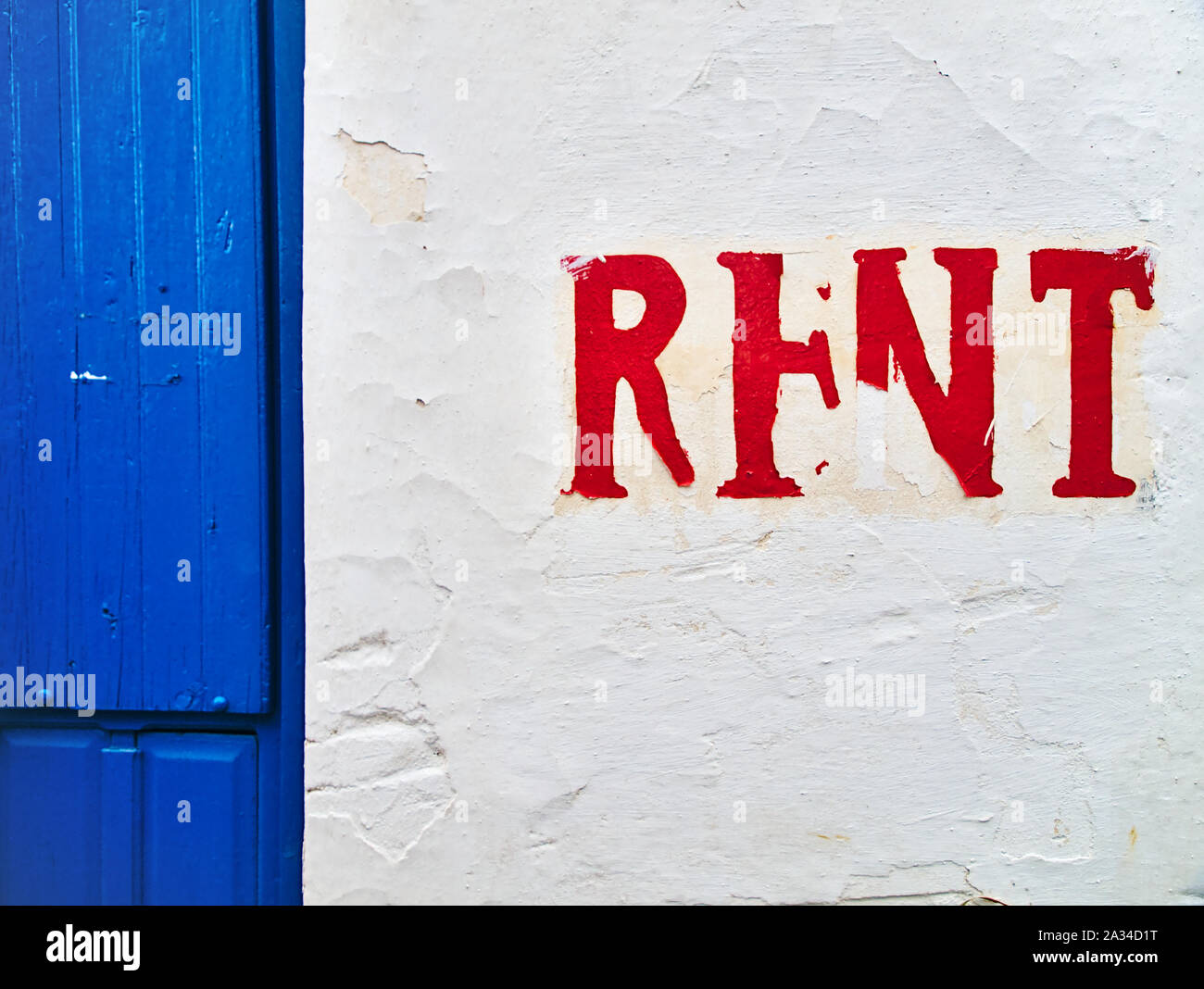 White wall with word rent written with red letters and wooden blue door ...