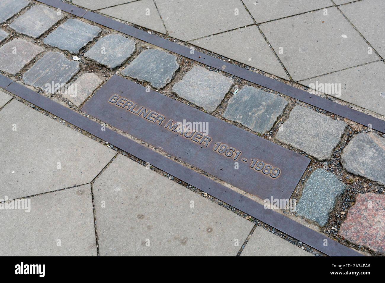 Sign and double row of cobblestones on a footpath in Berlin, Germany ...