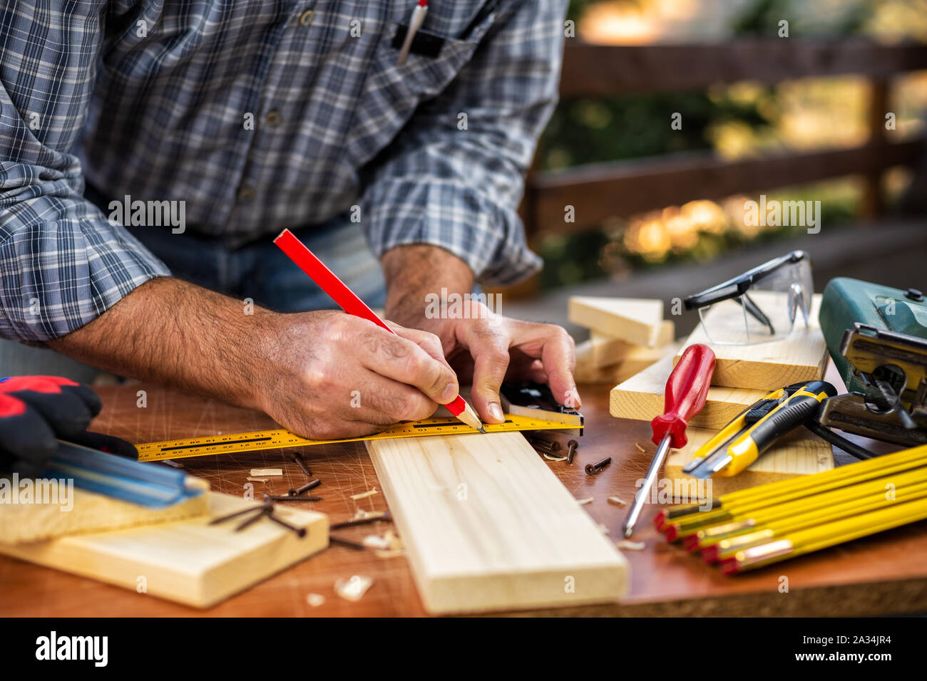 Carpenter with a pencil and the carpenter's square trace the cutting ...