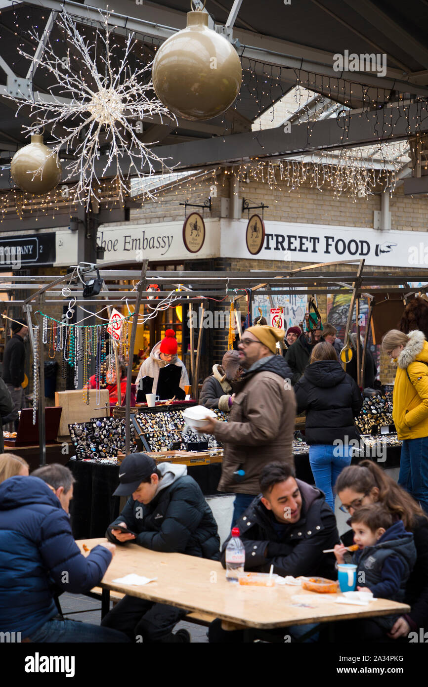 Diners sit and eat / eating meal at communal tables near food stall for ...