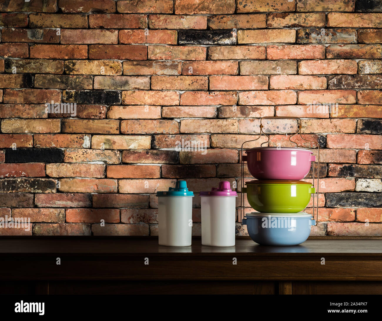 Colorful tiffin carrier and plastic cans on wooden cupboard in kitchen ...