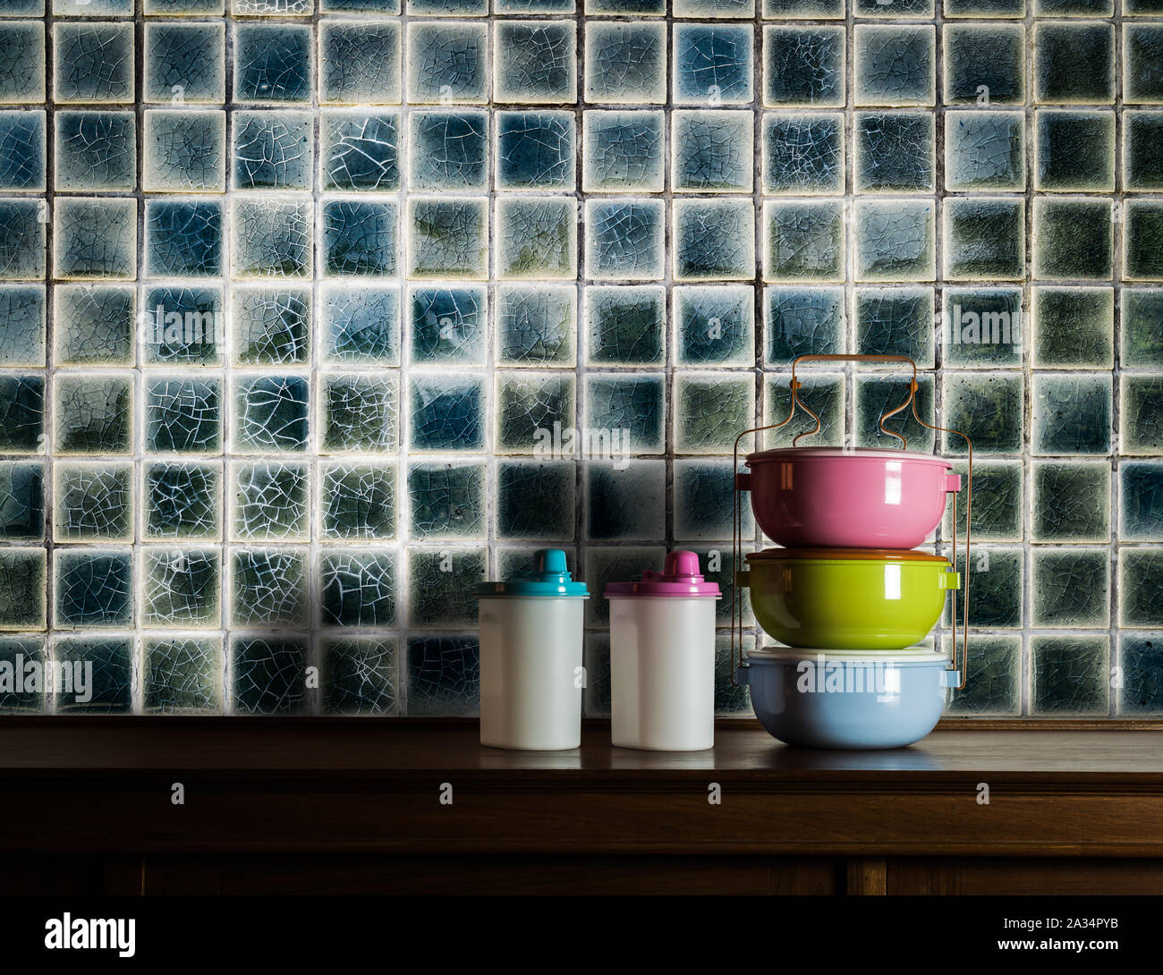 Colorful tiffin carrier and plastic cans on wooden cupboard in kitchen ...