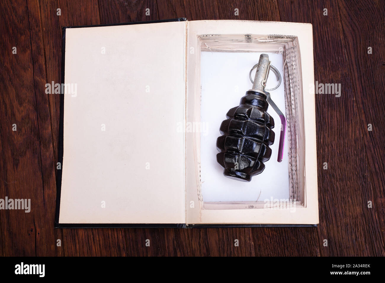 black hand grenade hidden in a book Stock Photo - Alamy