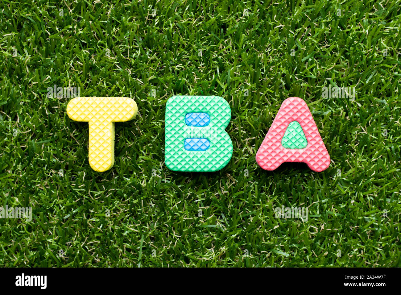 Toy foam letter in word TBA (abbreviation of to be announced) on green ...