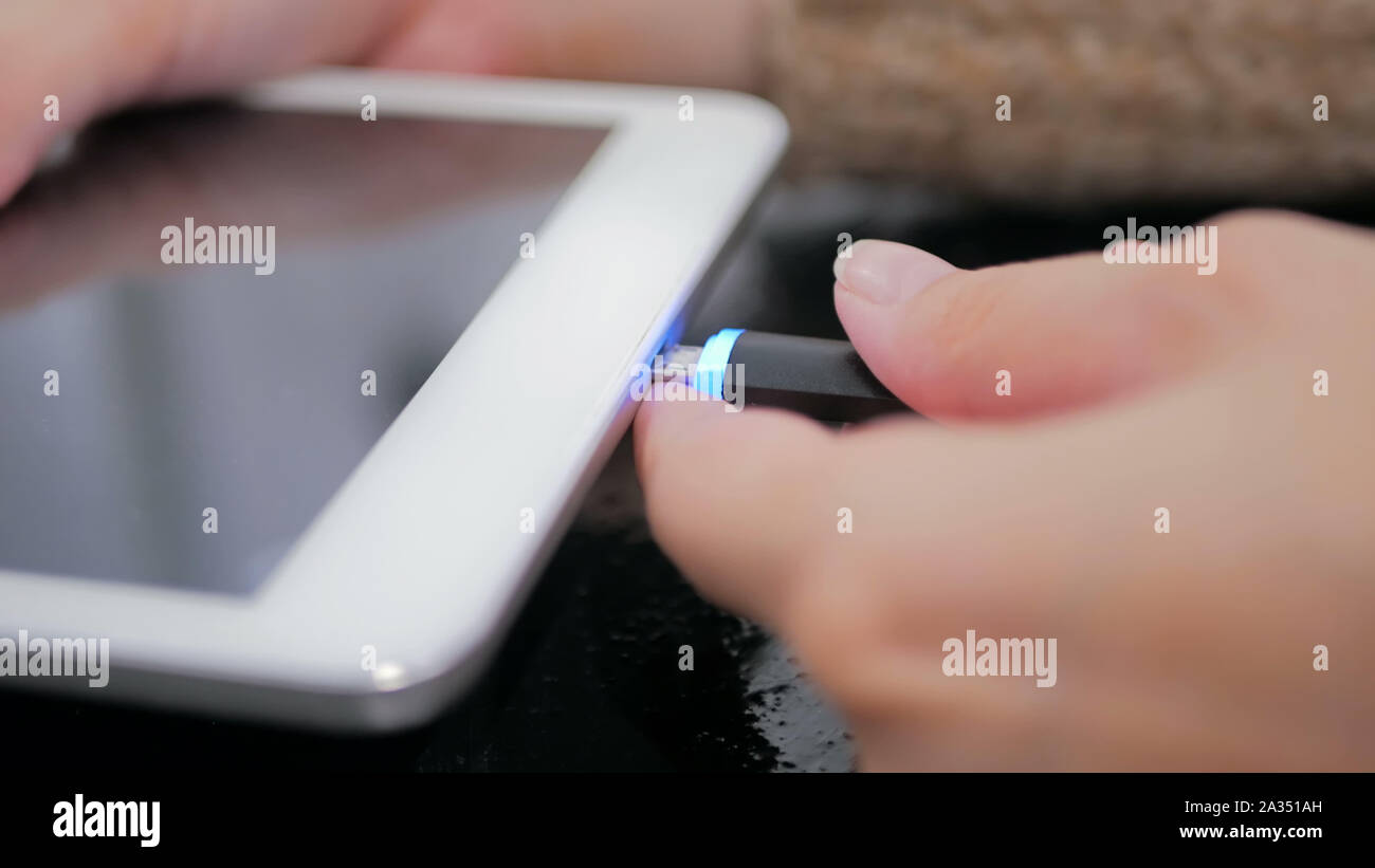 Woman's hand plugging black lightning charging cable into tablet Stock ...