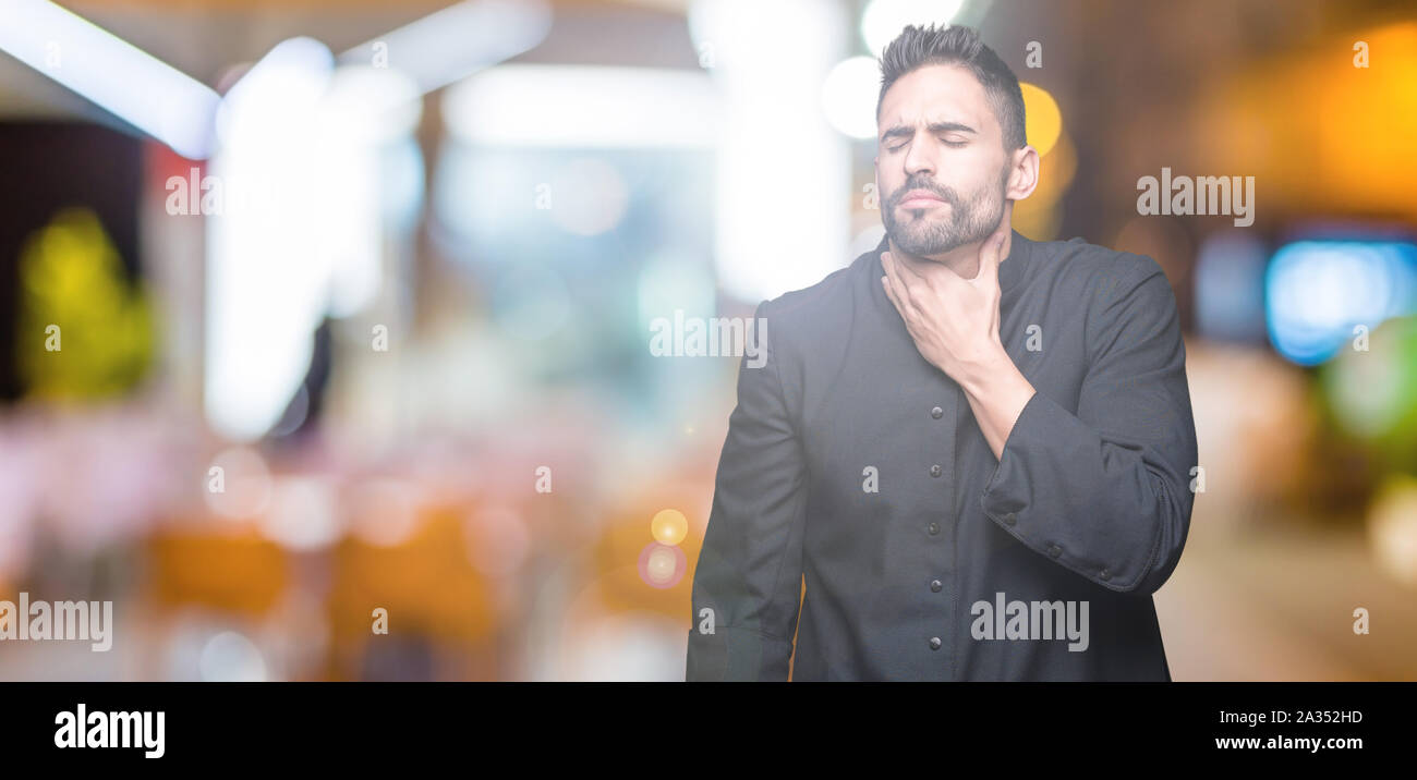 Young Christian priest over isolated background Touching painful neck ...