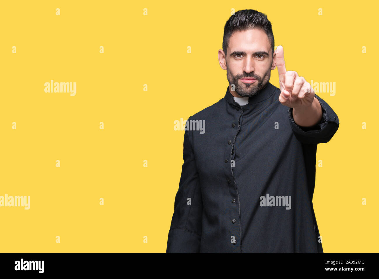 Young Christian priest over isolated background Pointing with finger up ...