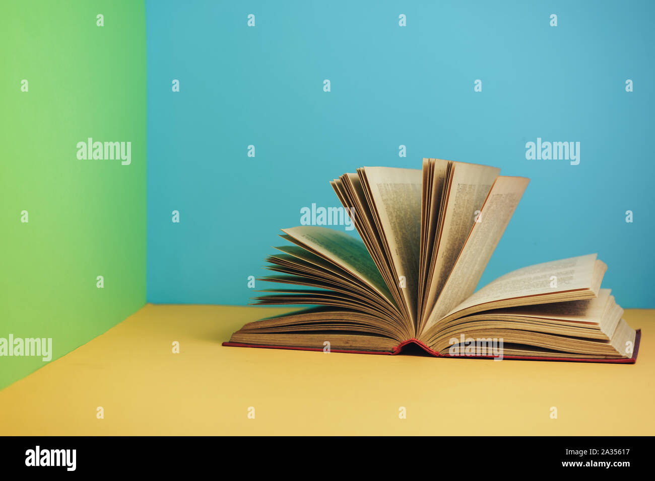 Beautiful open red book on a yellow table and green blue background ...