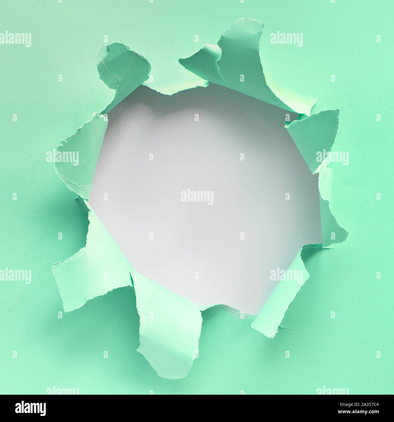 Green mint and white paper flat lay with ripped hole in the middle ...