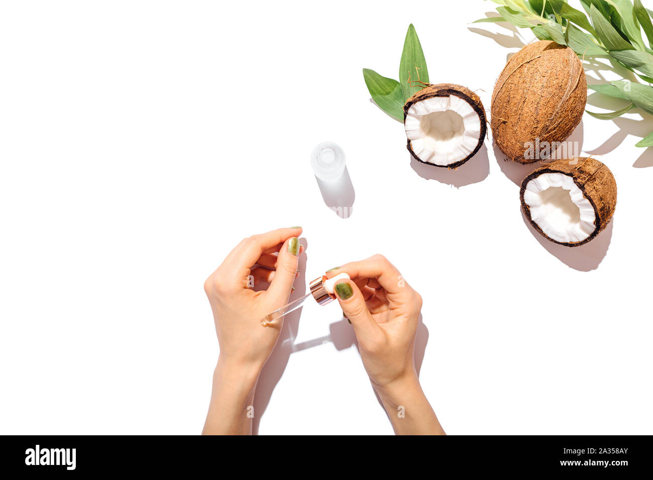 Female hands applying natural coconut oil next to fresh coconuts and ...