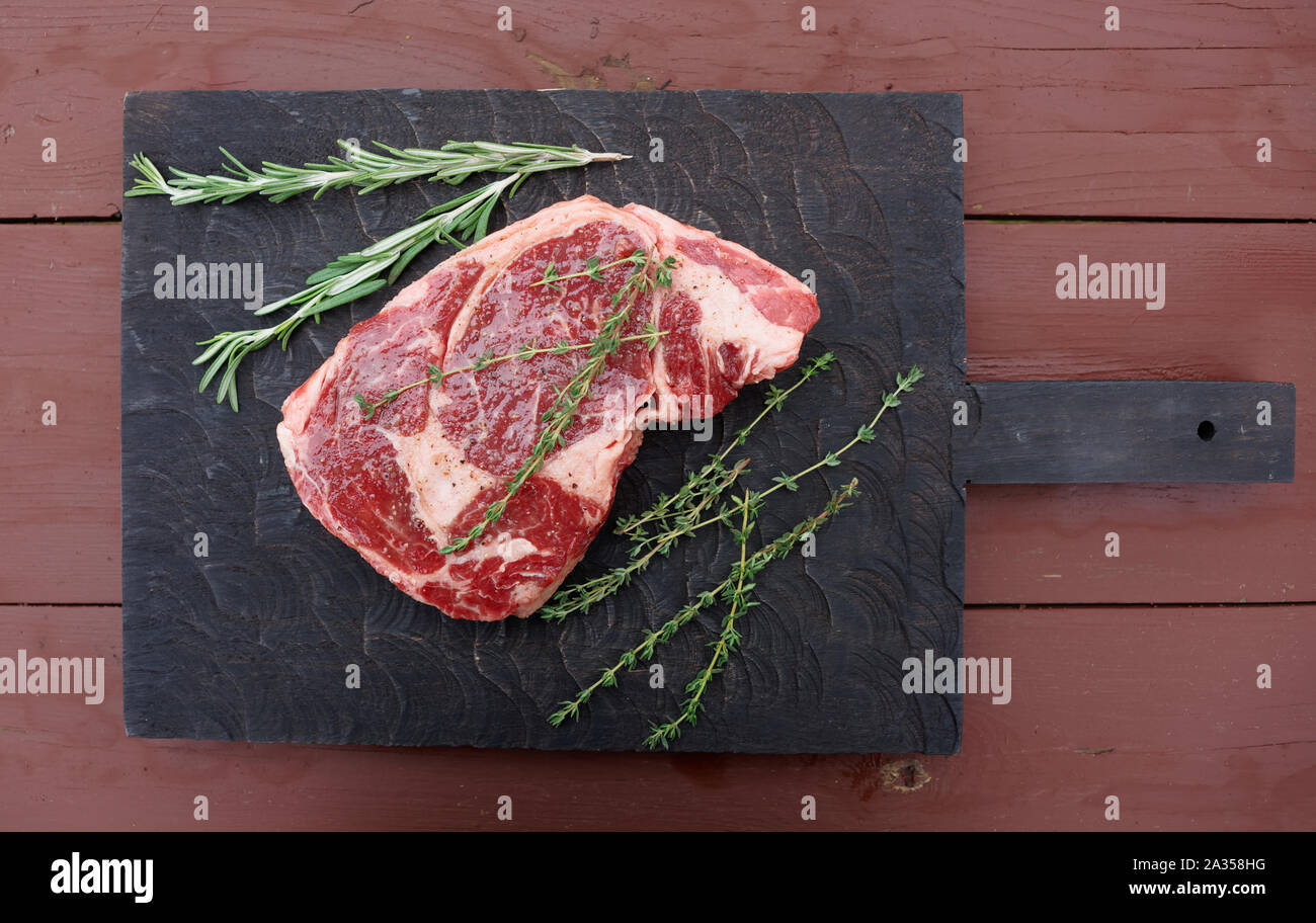 Raw rib-eye steak on black cutting board Stock Photo - Alamy