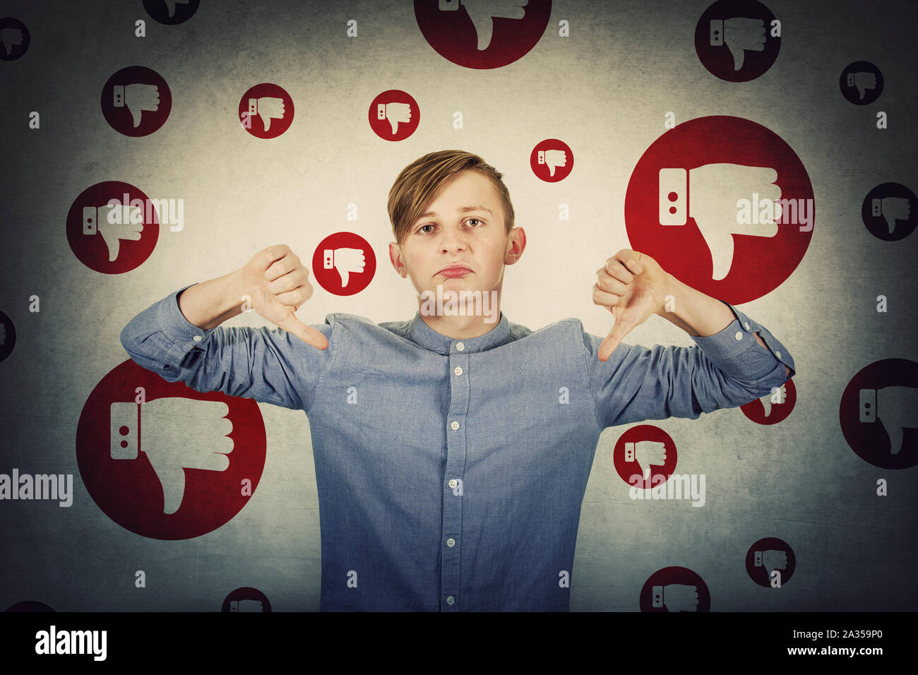 Displeased teenage boy showing both thumbs down, negative gesture and ...