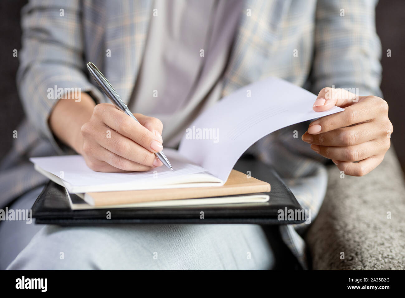 Contemporary young teacher with pen checking paper of one of students ...