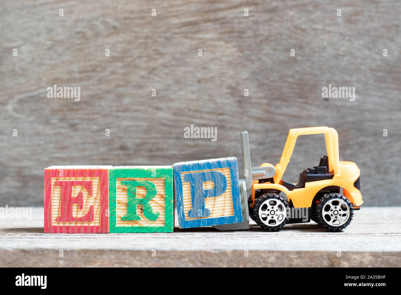 Toy forklift hold letter block P to complete word ERP (Abbreviation of ...