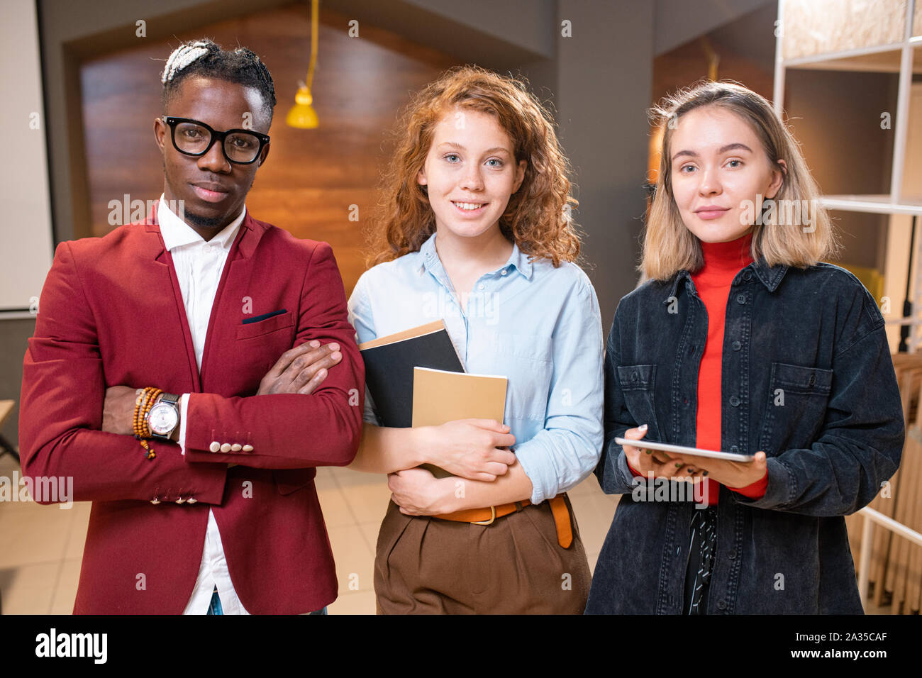 Three young intercultural college friends or groupmates in casualwear ...