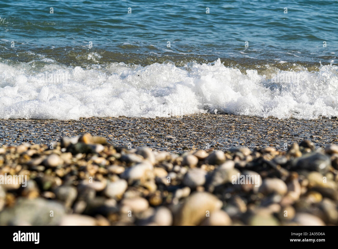 Sea wave on a pebble beach, foreground out of focus Stock Photo - Alamy
