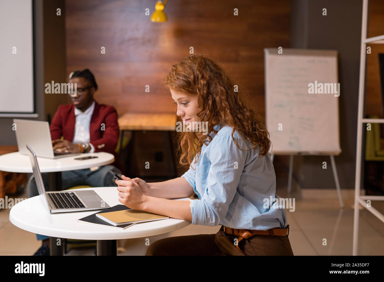 Pretty young casual woman with smartphone texting in college cafe by ...