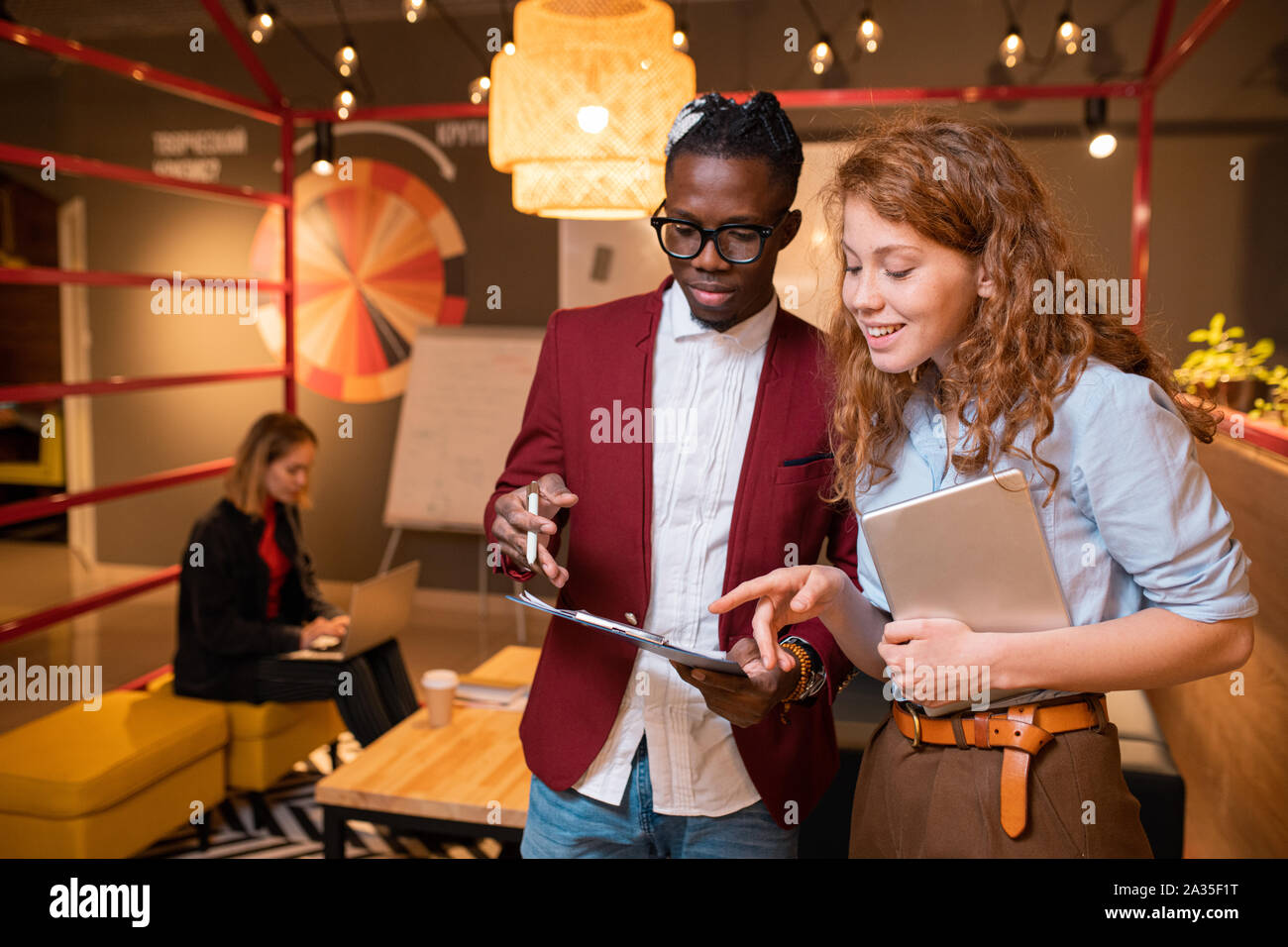 Two young casual multicultural financiers discussing financial document ...