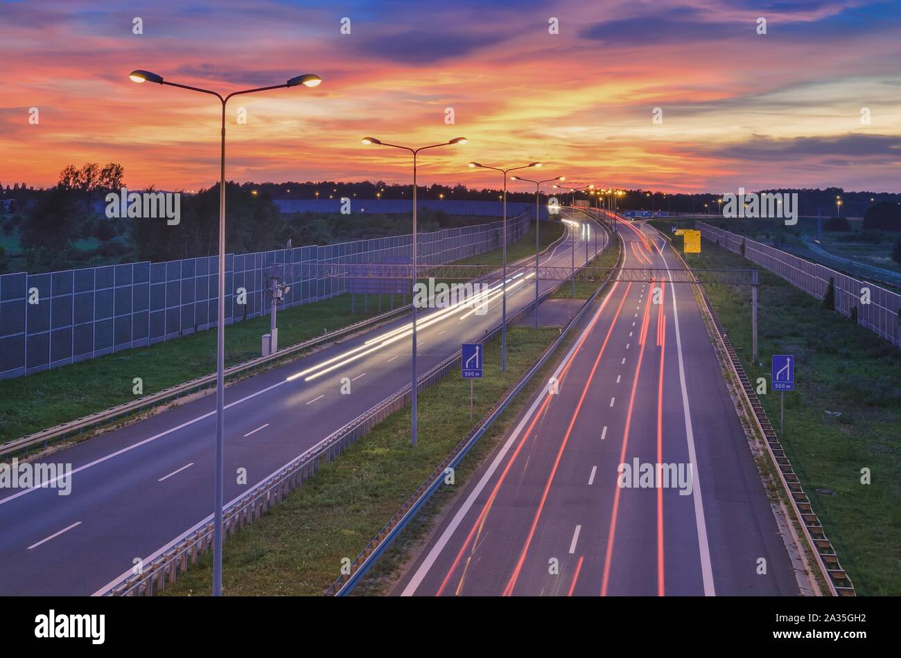 Highway at night. Beautiful colorful sky with the setting light over ...
