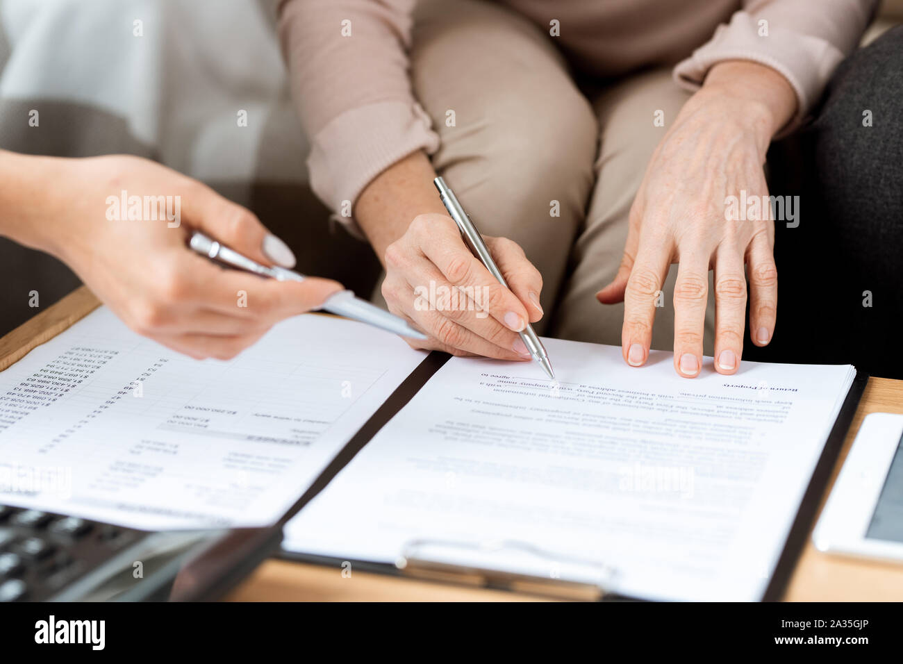 Hands of mature client and real estate agent with pens pointing at ...