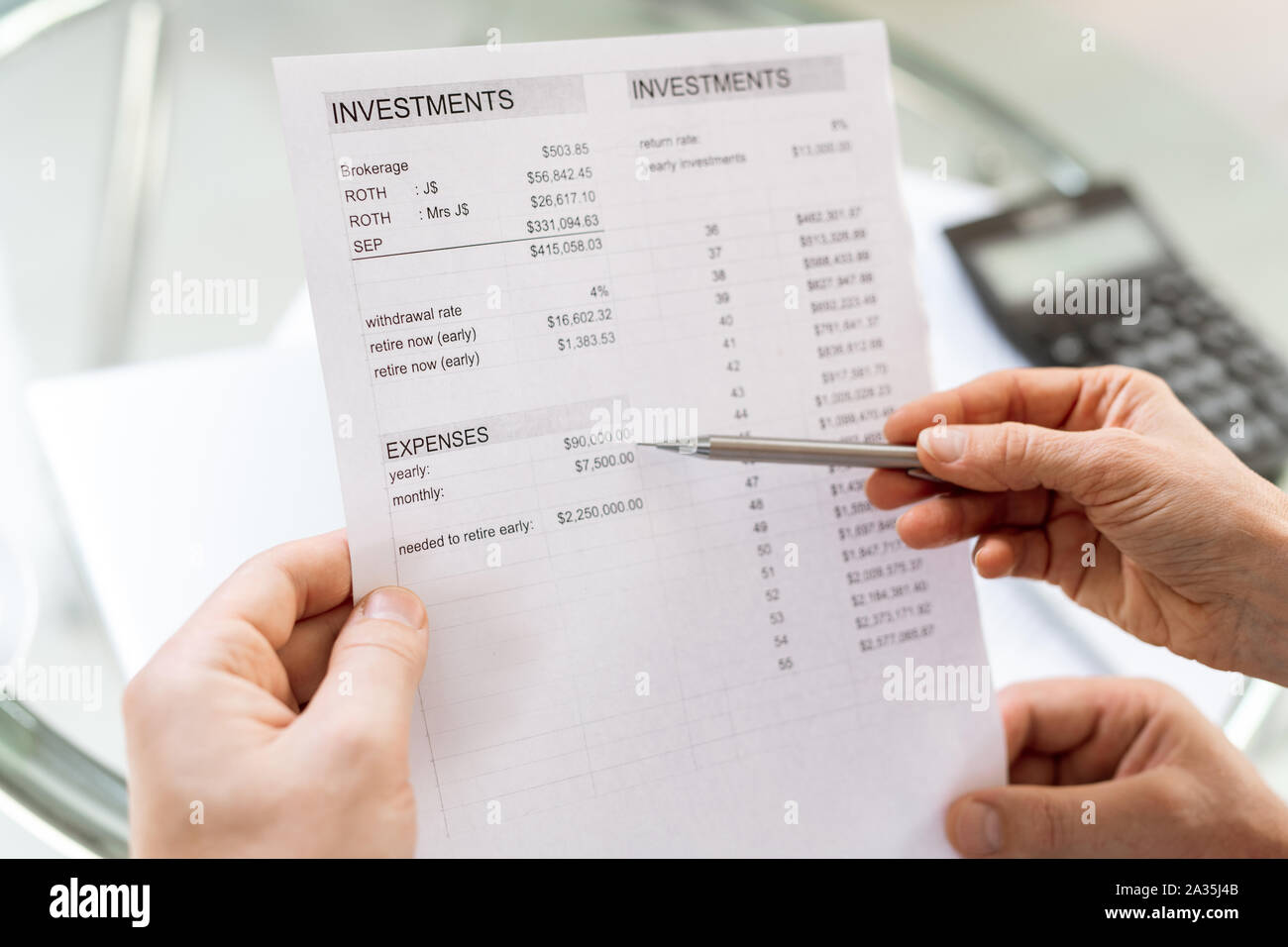 Human hand holding pen while pointing at sum of money in financial ...