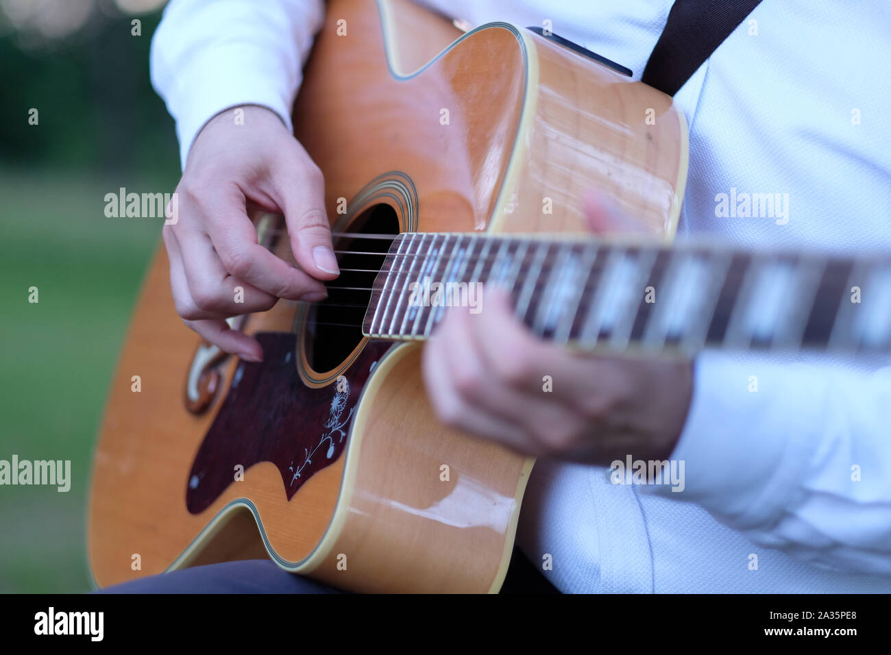 A six-stringed acoustic jumbo guitar in the hands of a musician Stock ...