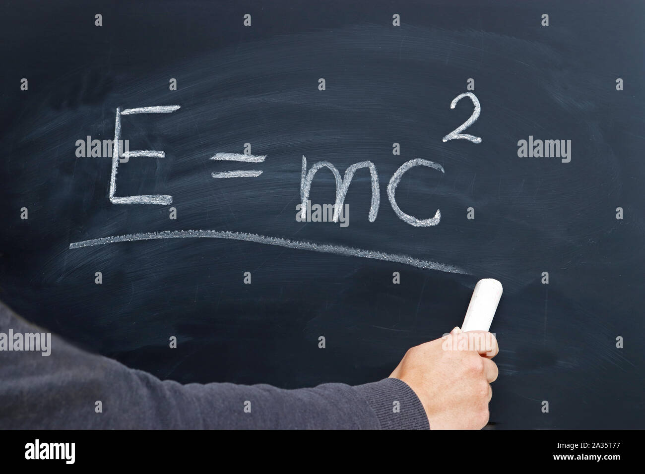 hand of a young person writing the Einstein formula on a blackboard ...