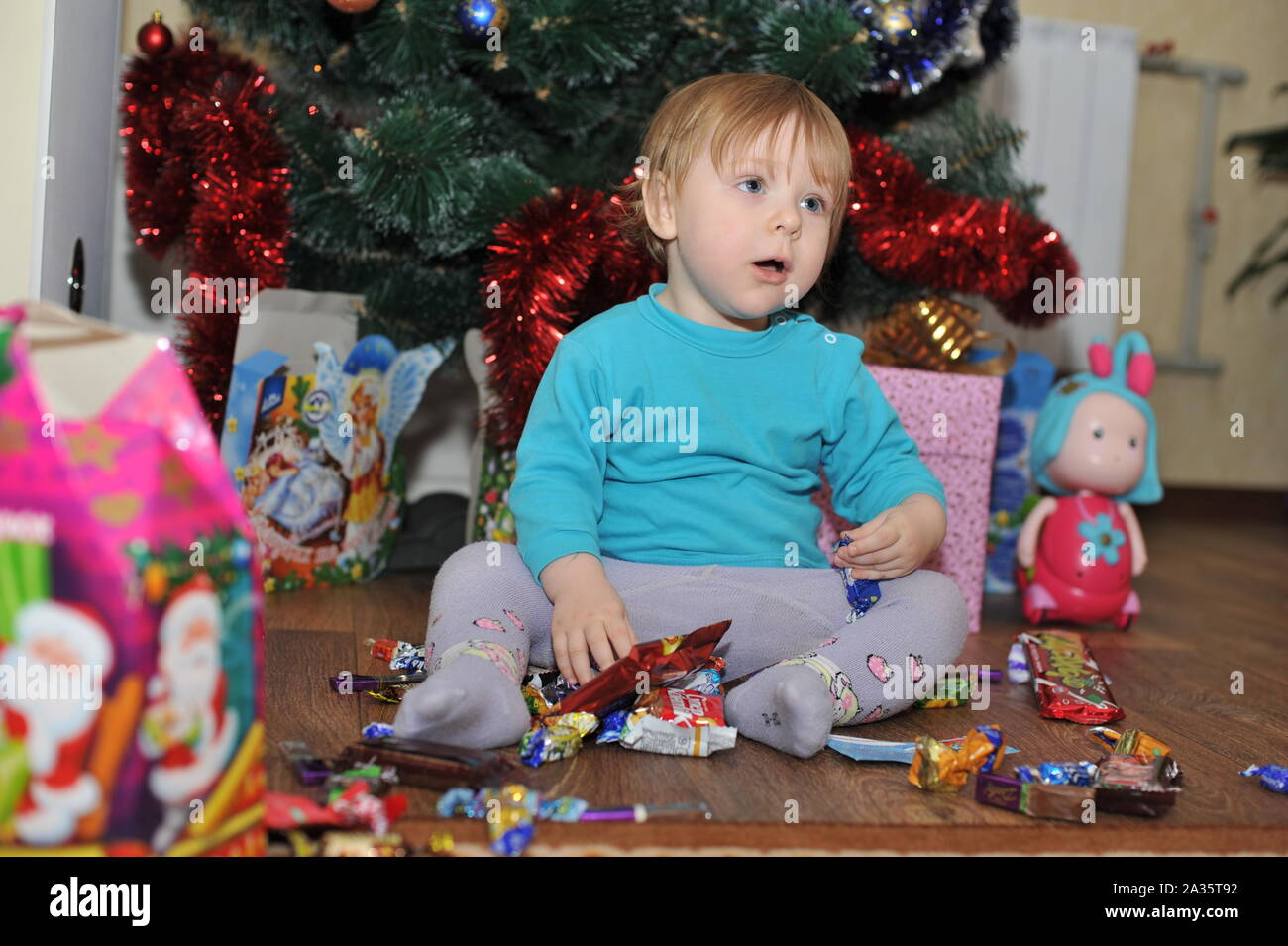 The little girl under the Christmas tree. baby girl with gifts under ...