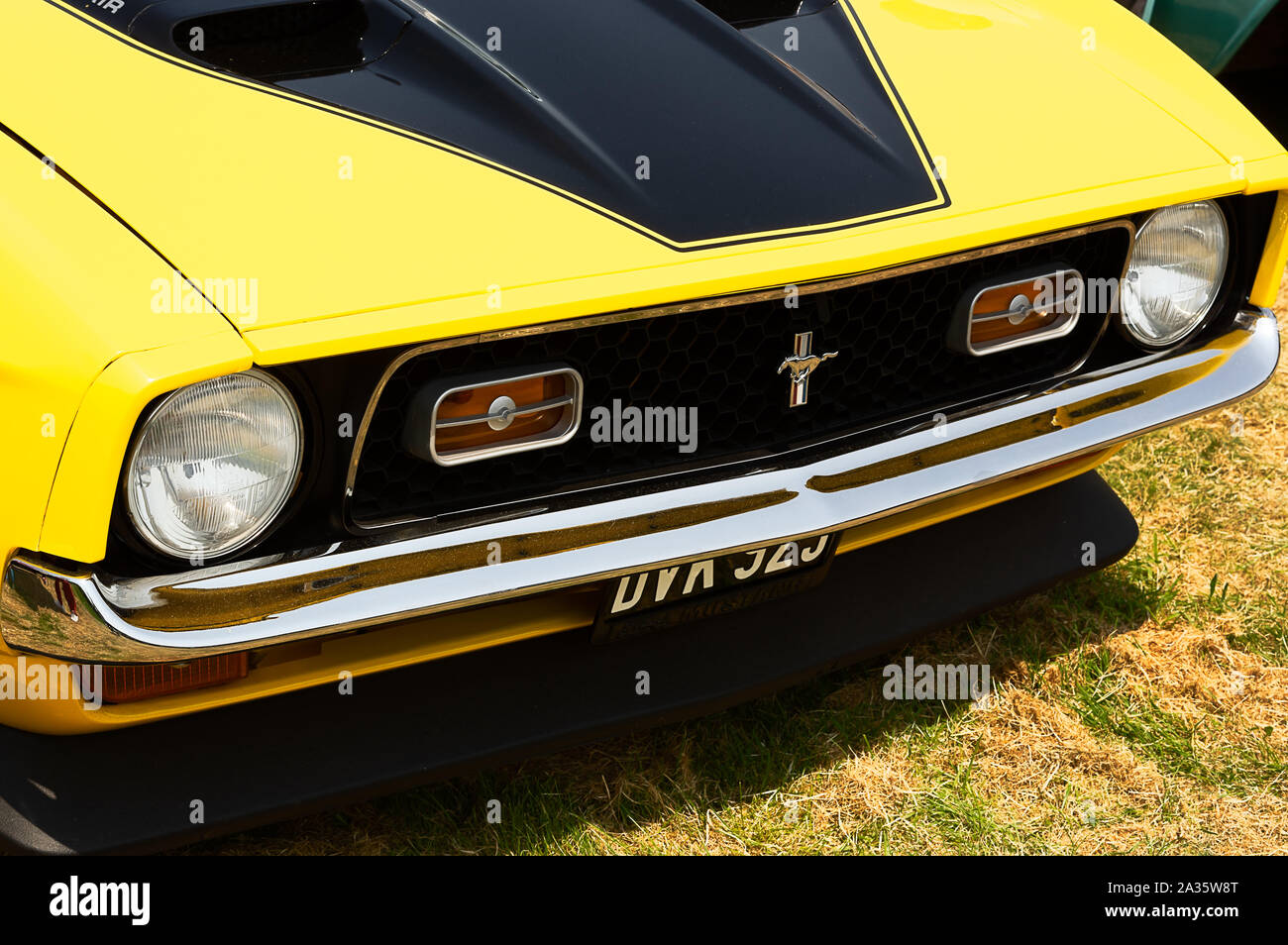 The front of a yellow 1970's Ford Mustang on display at a car show ...